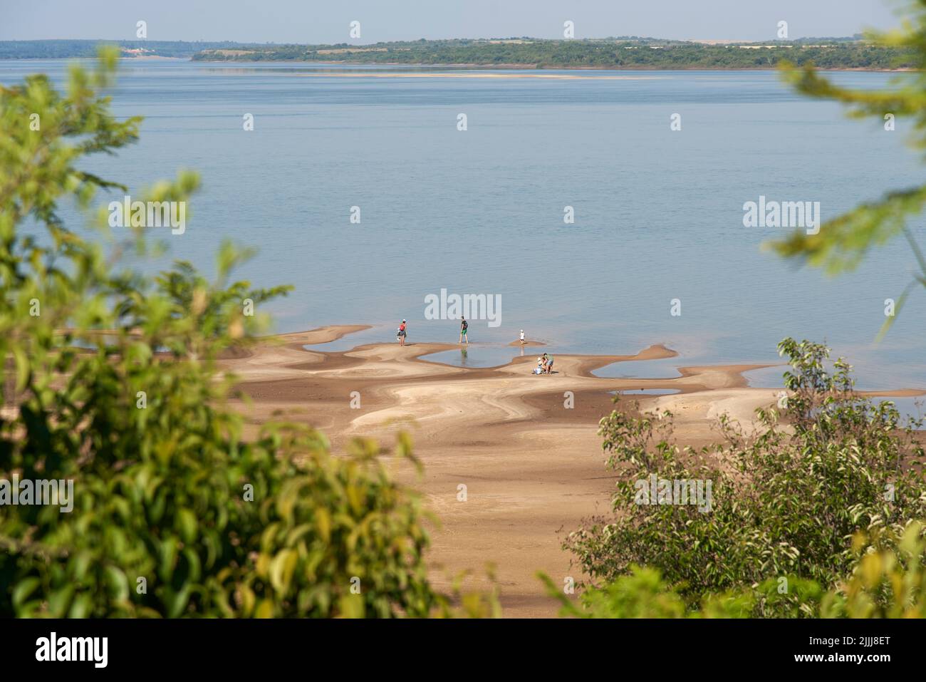 Summer landscape, distant view of people enjoying the beach of a river ...