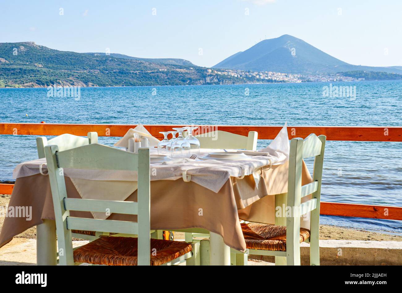 Typical Greek seaside tavern table with wooden chairs by the sea coast ...