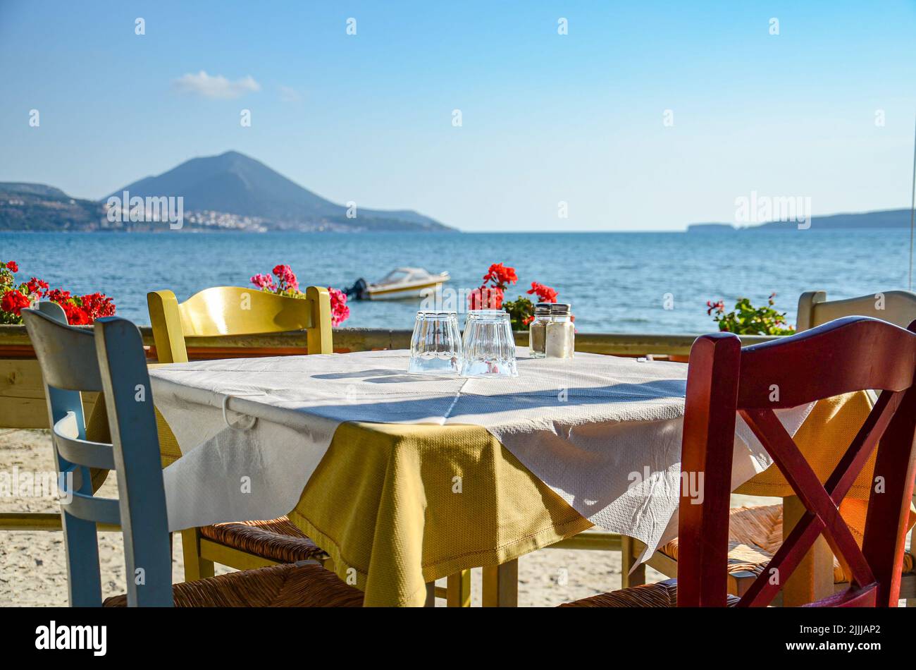 Typical Greek seaside tavern table with wooden chairs by the sea coast ...