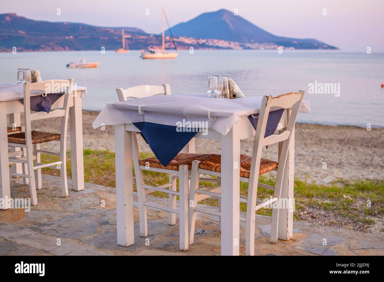 Typical Greek seaside tavern table with wooden chairs by the sea coast ...