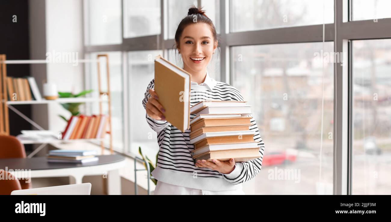 Beautiful female student with stack of books in library Stock Photo - Alamy