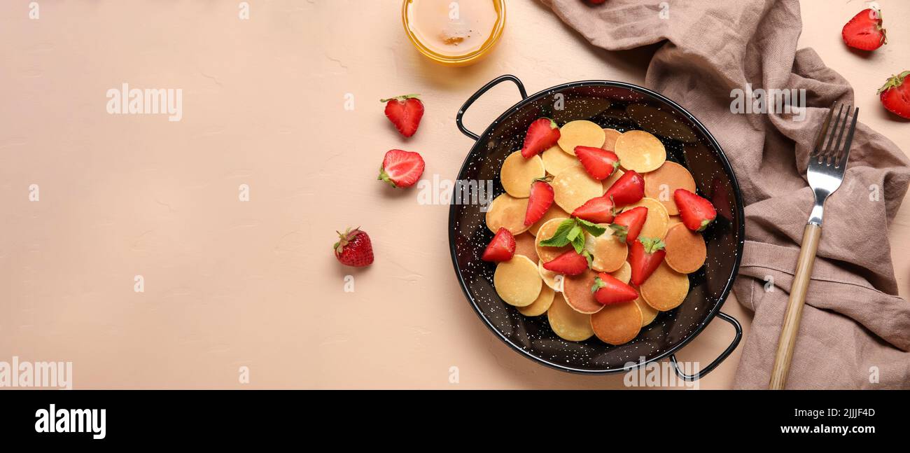 Composition with frying pan of mini pancakes and strawberry on beige ...