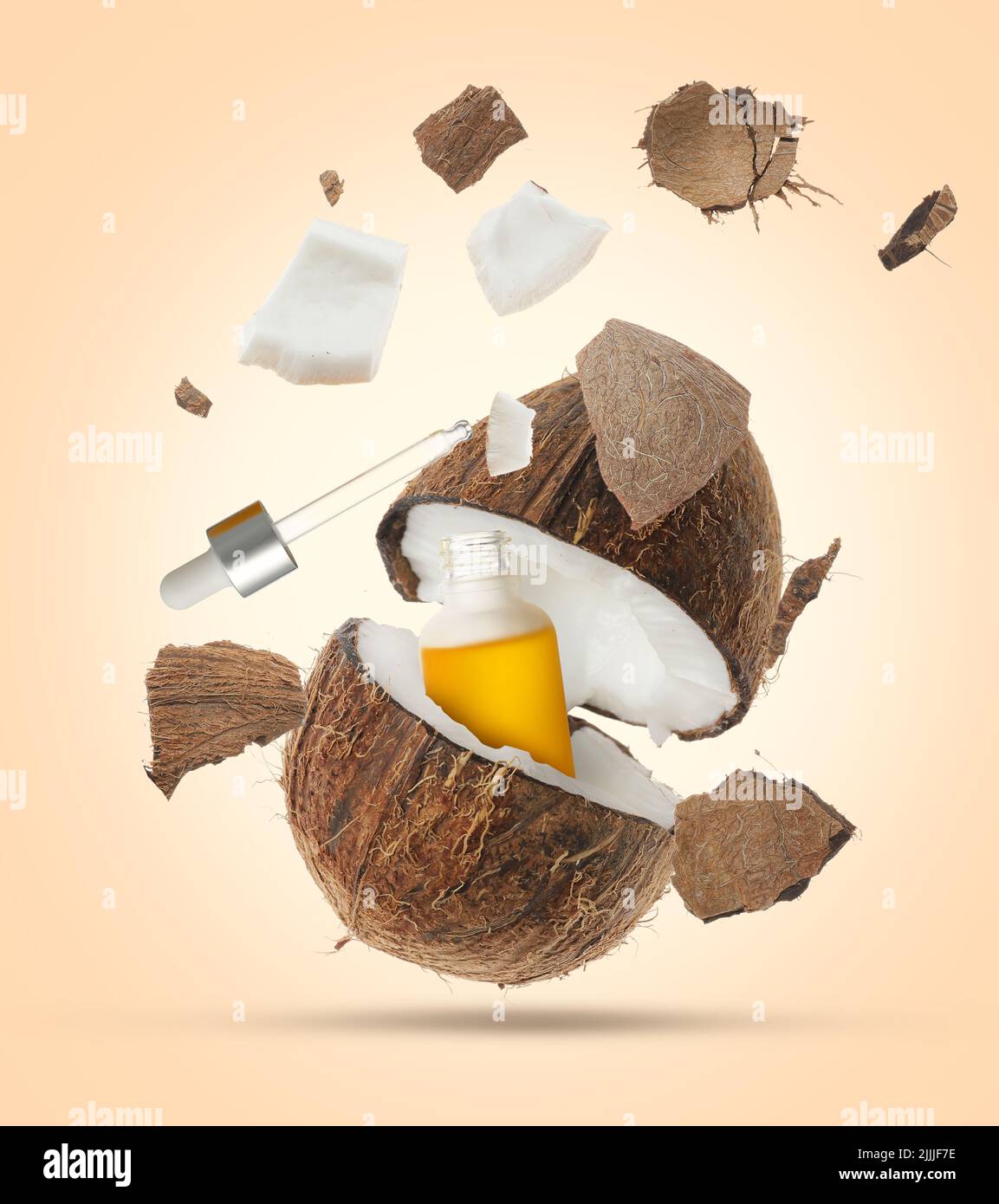 Cracked coconut and bottle of essential oil on beige background Stock ...