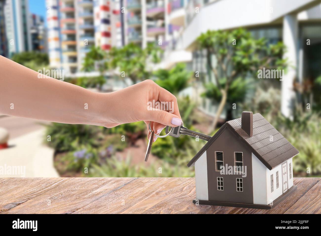 Hand with key and figure of house outdoors. Concept of buying real ...