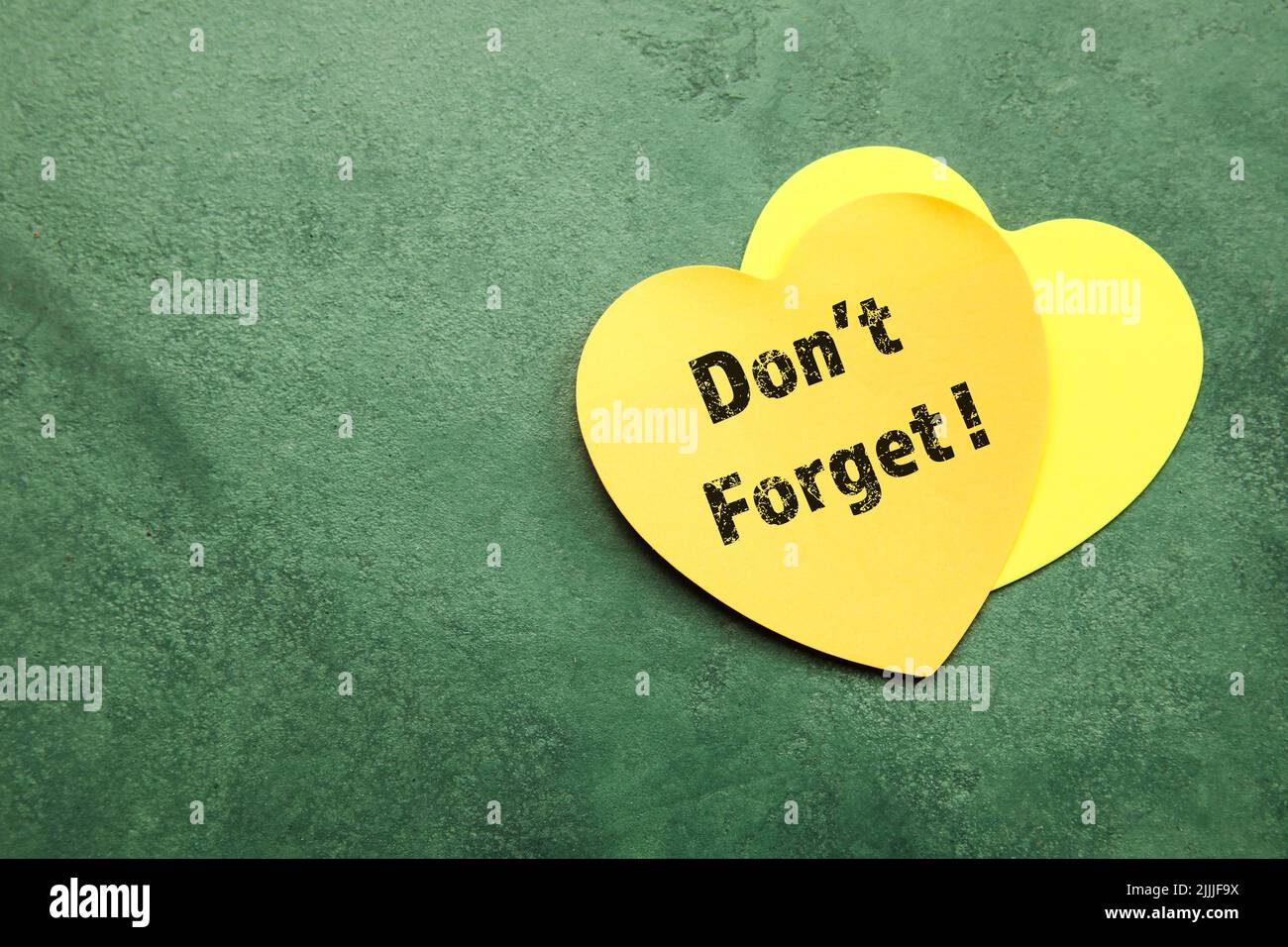 Heart shaped sticky note with text DON'T FORGET on green background ...