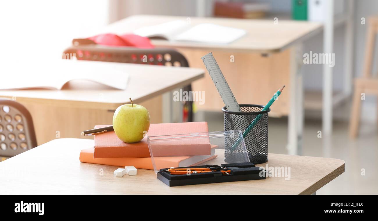 Apple and school stationery on desk in classroom Stock Photo - Alamy
