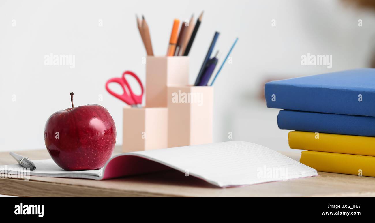 Apple and school stationery on desk in classroom Stock Photo - Alamy