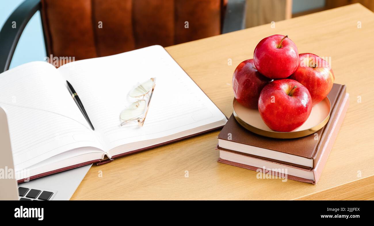 Apples and books on teacher's table in classroom Stock Photo - Alamy