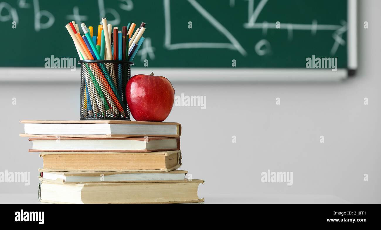 Apple, books and school stationery in classroom Stock Photo - Alamy