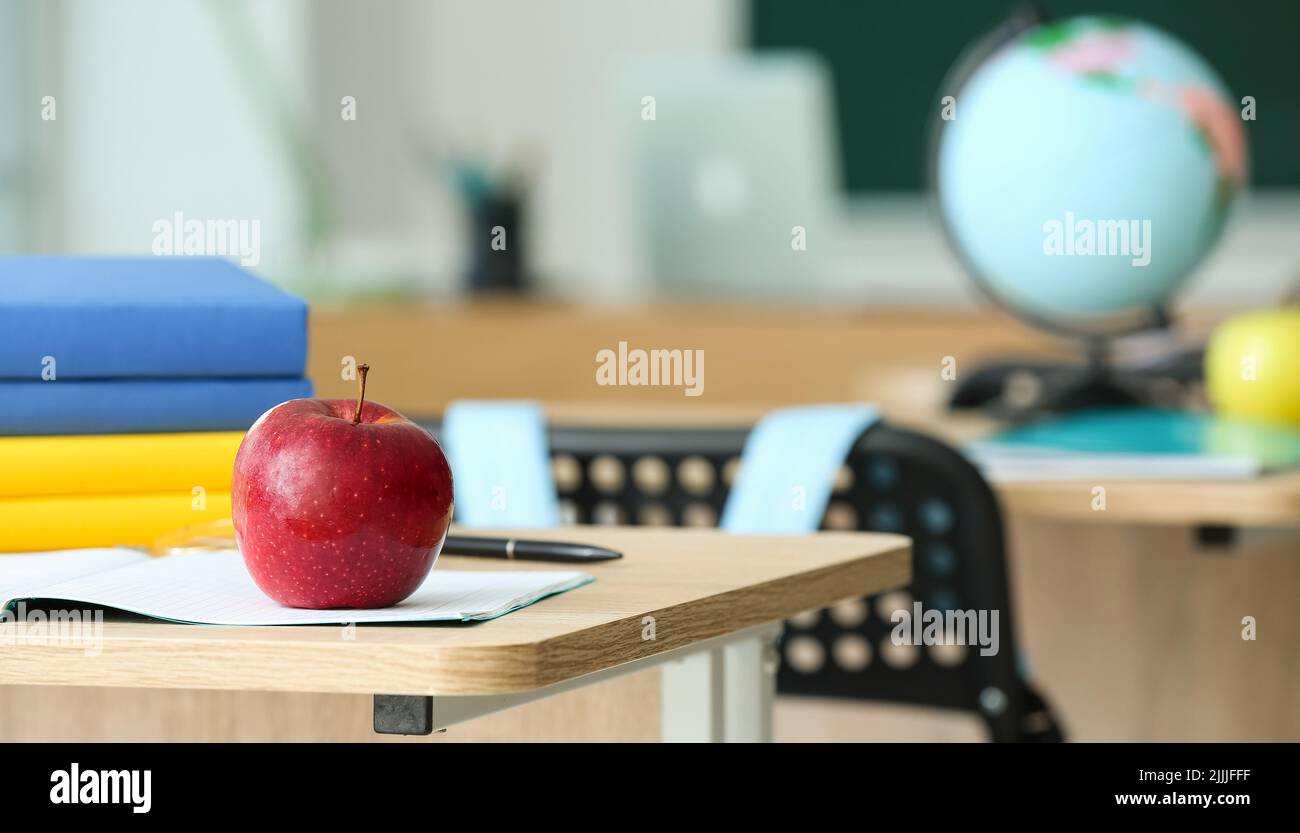 Apple and school stationery on desk in classroom Stock Photo - Alamy