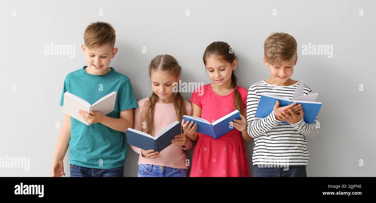 Cute little children reading books on grey background Stock Photo - Alamy