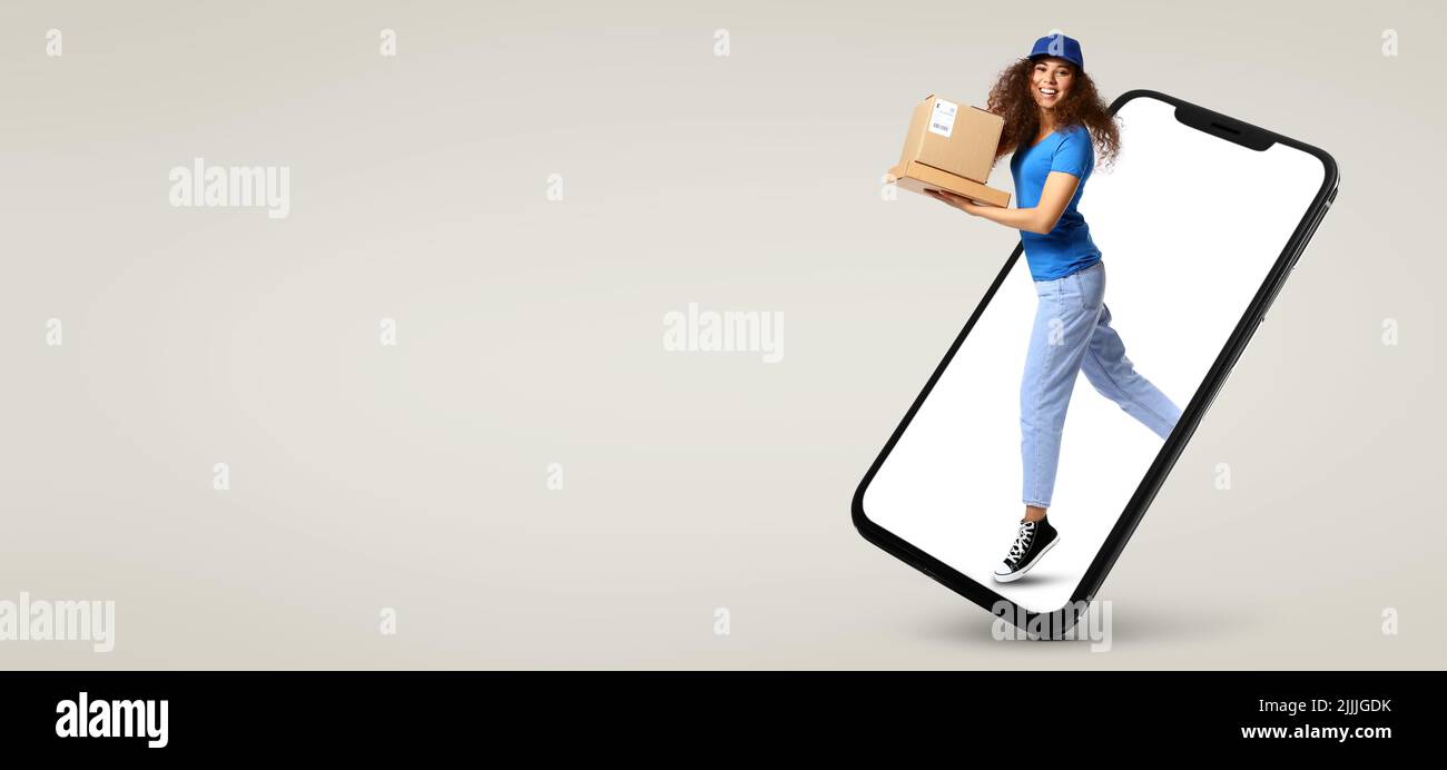 Female African-American courier with parcels jumping out of smartphone ...