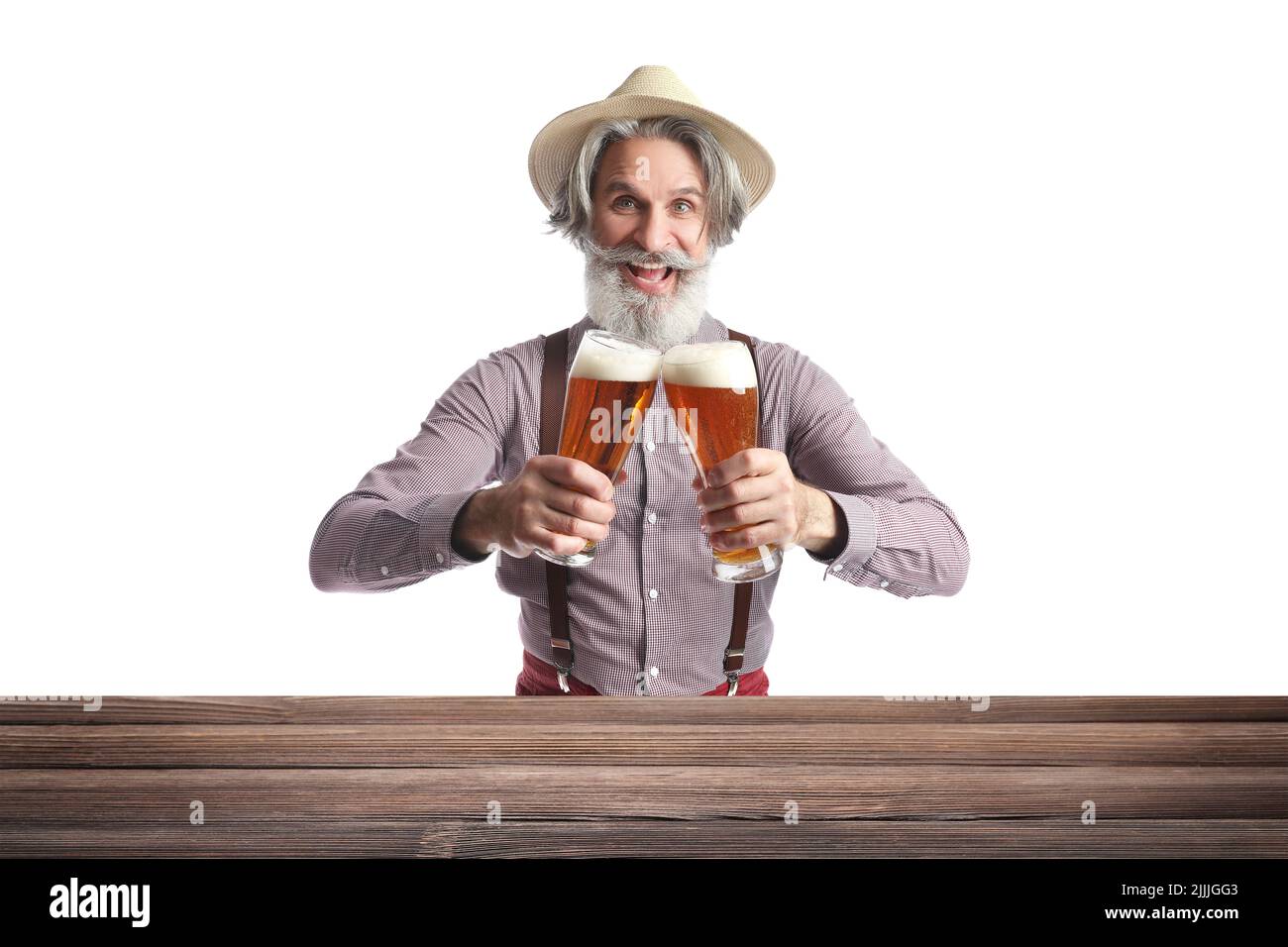 Mature man in traditional German clothe and with beer at table on white ...