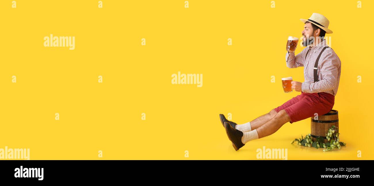 Handsome man in traditional German clothes drinking beer on yellow ...