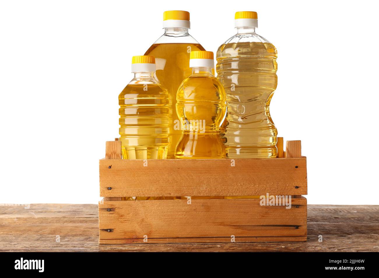 Bottles with sunflower oil in crate on wooden table against white ...