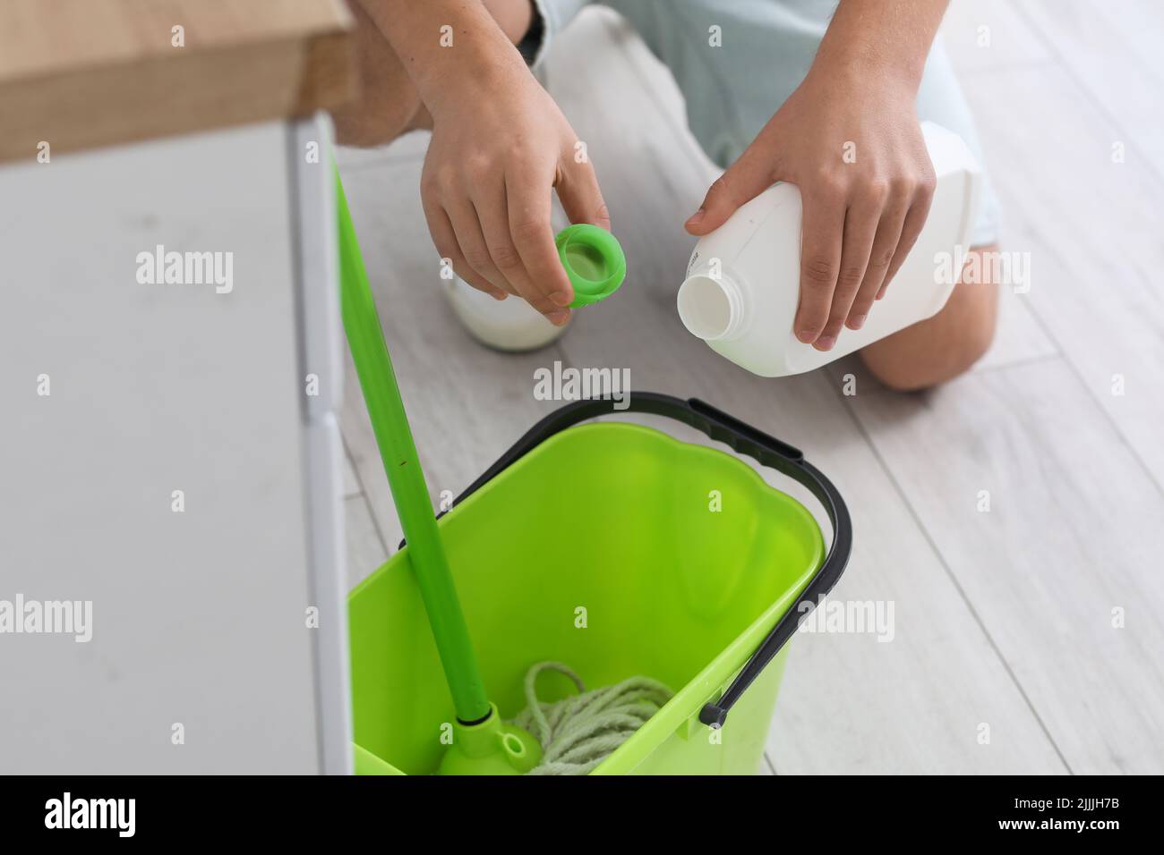 Young man pouring detergent into bucket in kitchen, closeup Stock Photo ...