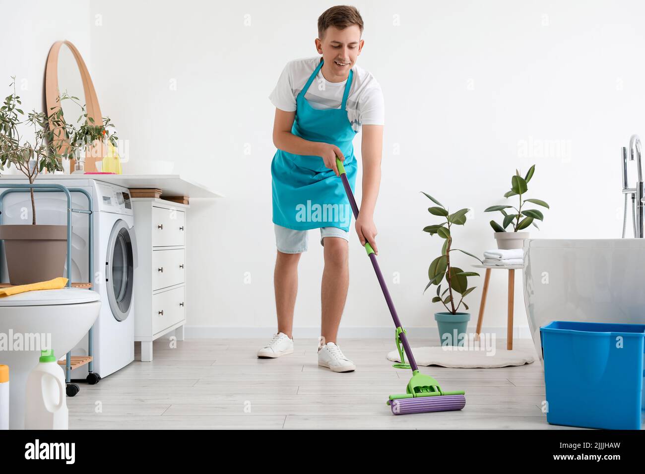 Young man mopping floor in modern bathroom Stock Photo - Alamy