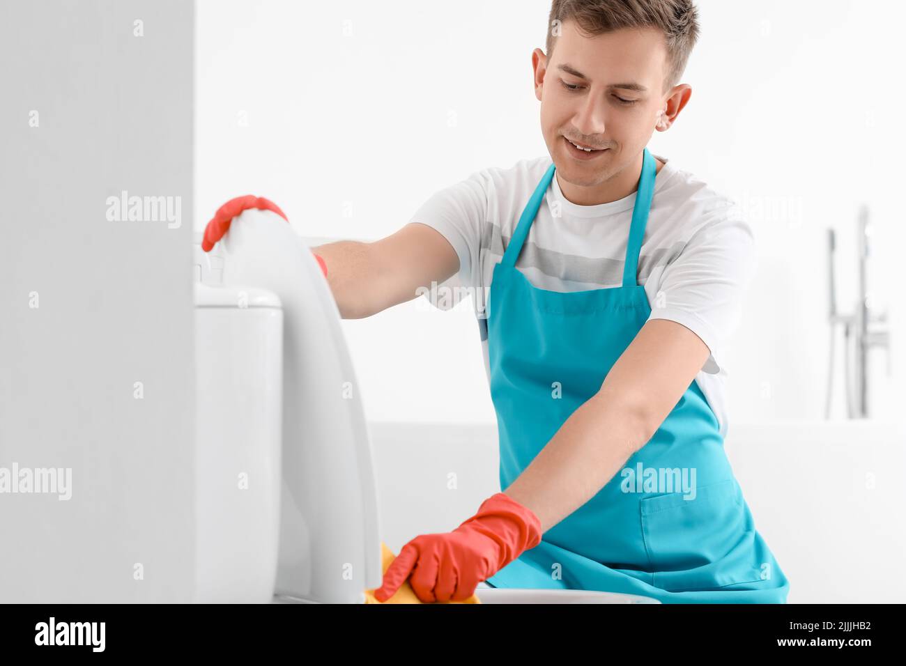 Young man cleaning toilet bowl with rag in bathroom Stock Photo - Alamy