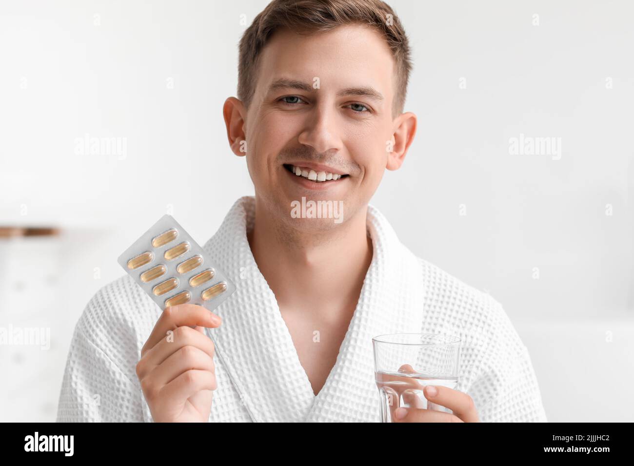 Young man with pills and glass of water in bathroom, closeup Stock ...