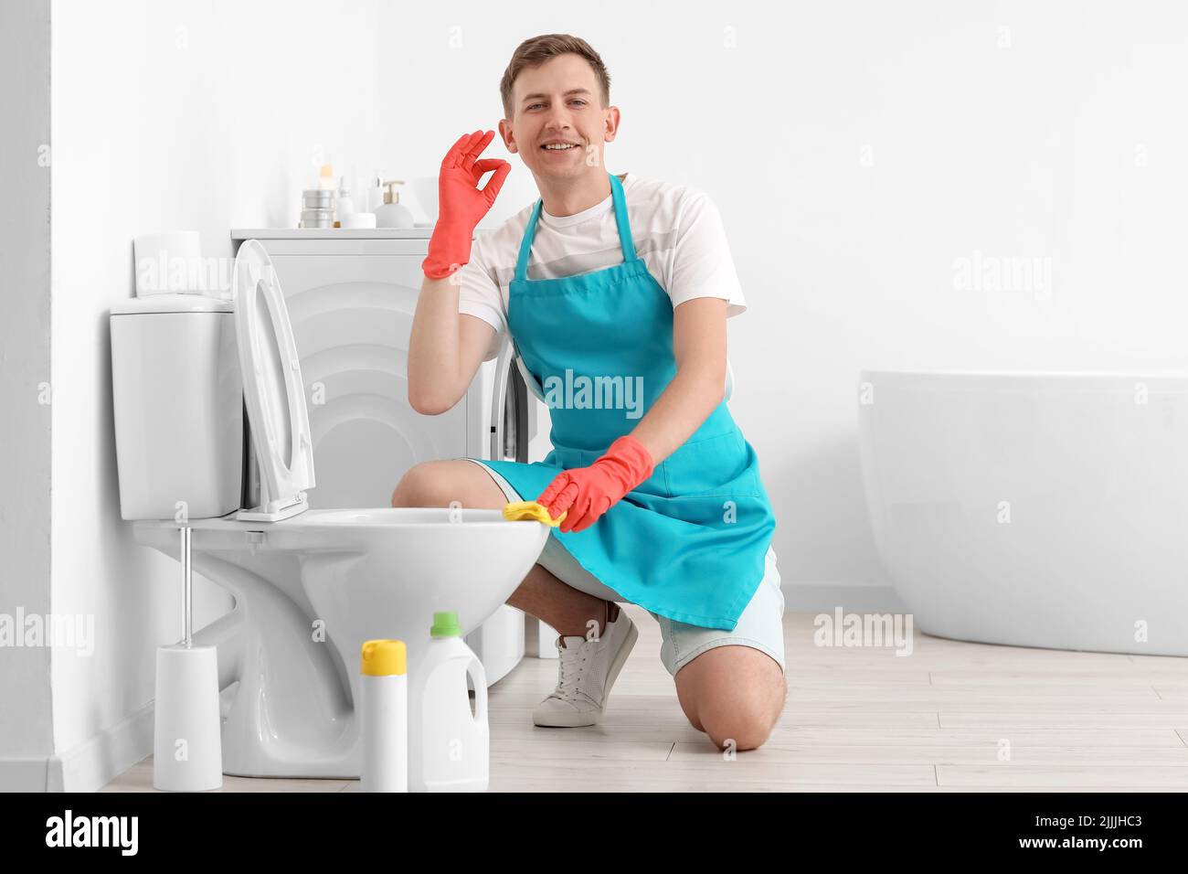 Young man cleaning toilet bowl and showing OK in bathroom Stock Photo ...