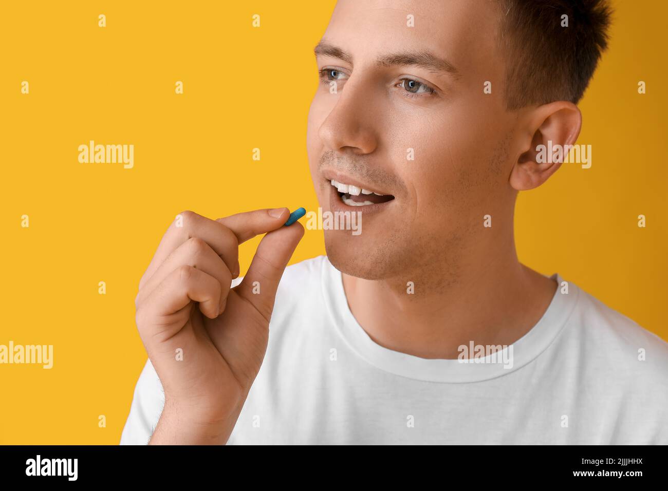 Young man taking vitamin on yellow background, closeup Stock Photo - Alamy