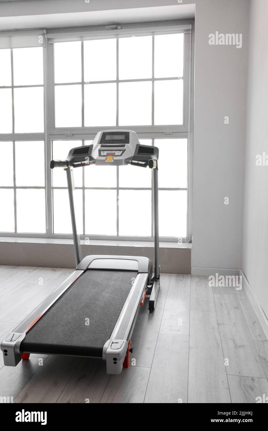 Modern treadmill near window in room Stock Photo - Alamy