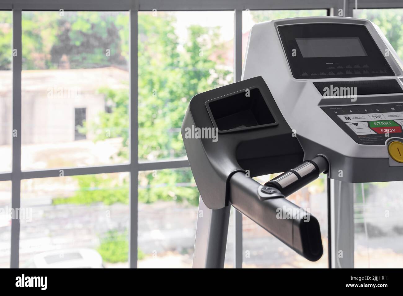 Modern treadmill near window in gym, closeup Stock Photo - Alamy
