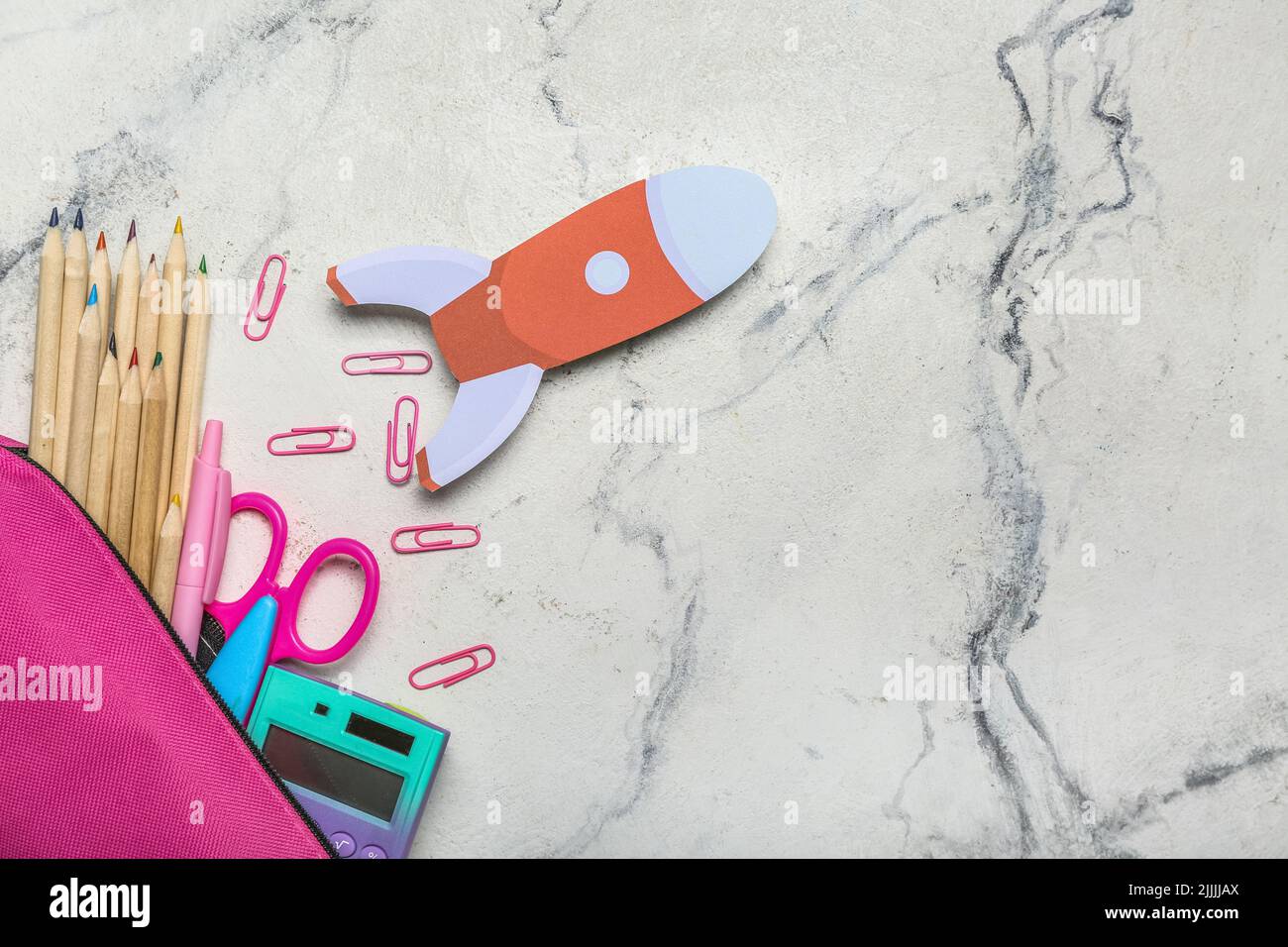 Pencil case with school stationery and paper rocket on light background ...