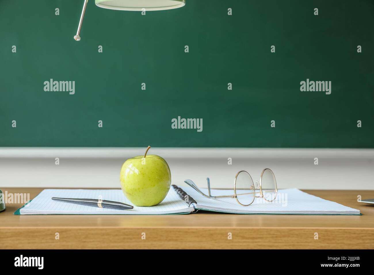 Apple with eyeglasses, pen and copybook on table near chalkboard Stock ...