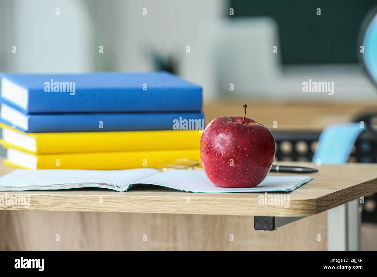 Apple with school books on table in classroom, closeup Stock Photo - Alamy