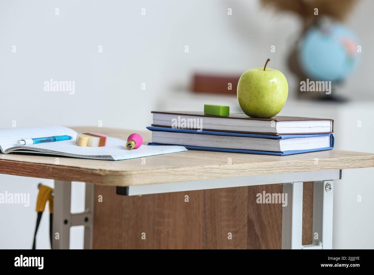 Apple with school books and erasers on table in classroom Stock Photo ...