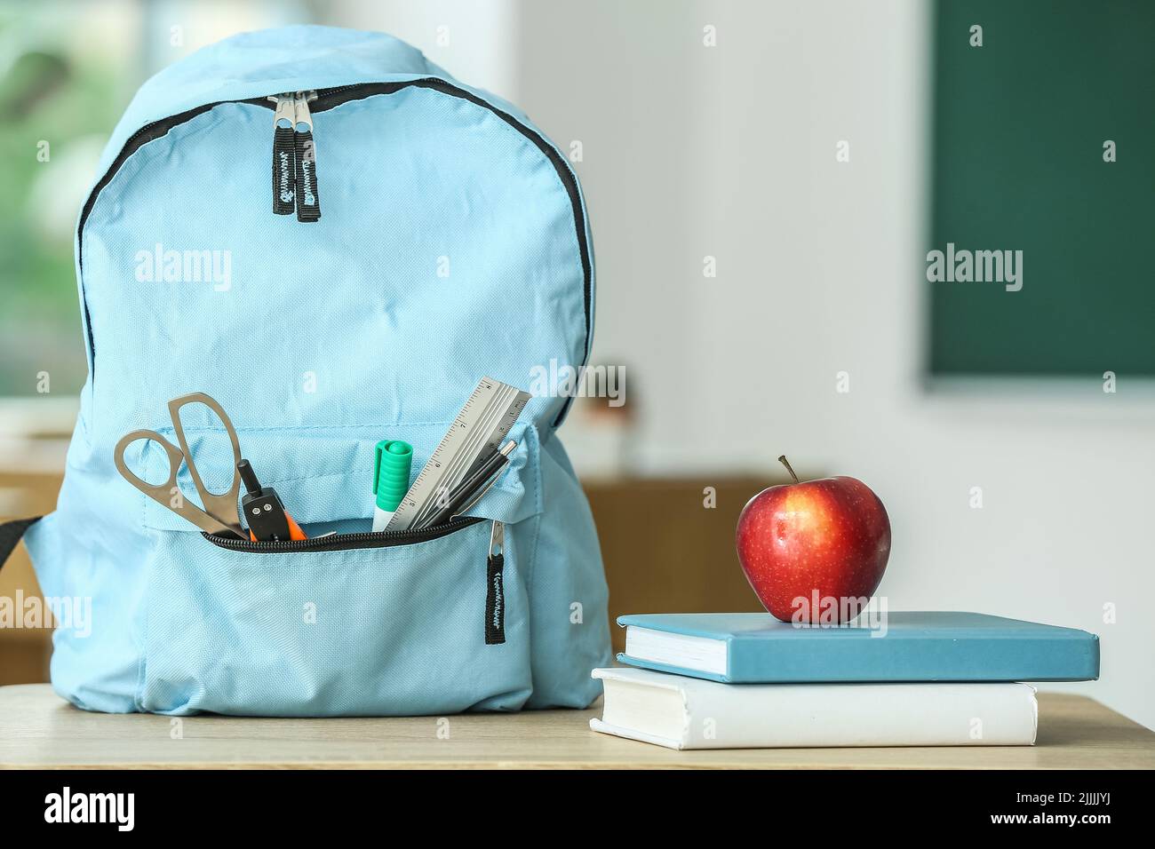Apple with school books and backpack on table in classroom Stock Photo ...