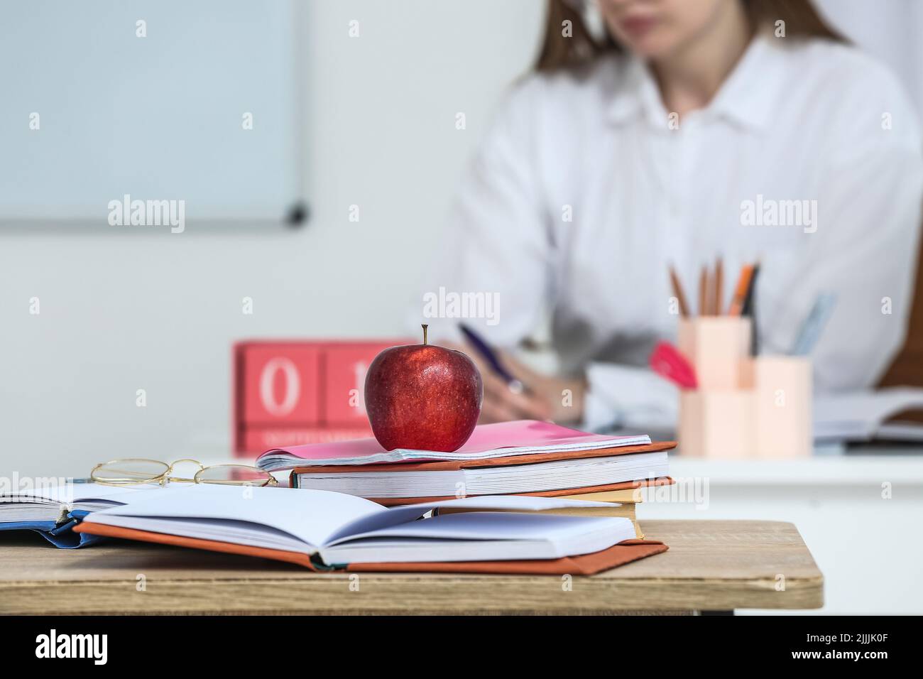 Apple with school books on table in classroom Stock Photo - Alamy