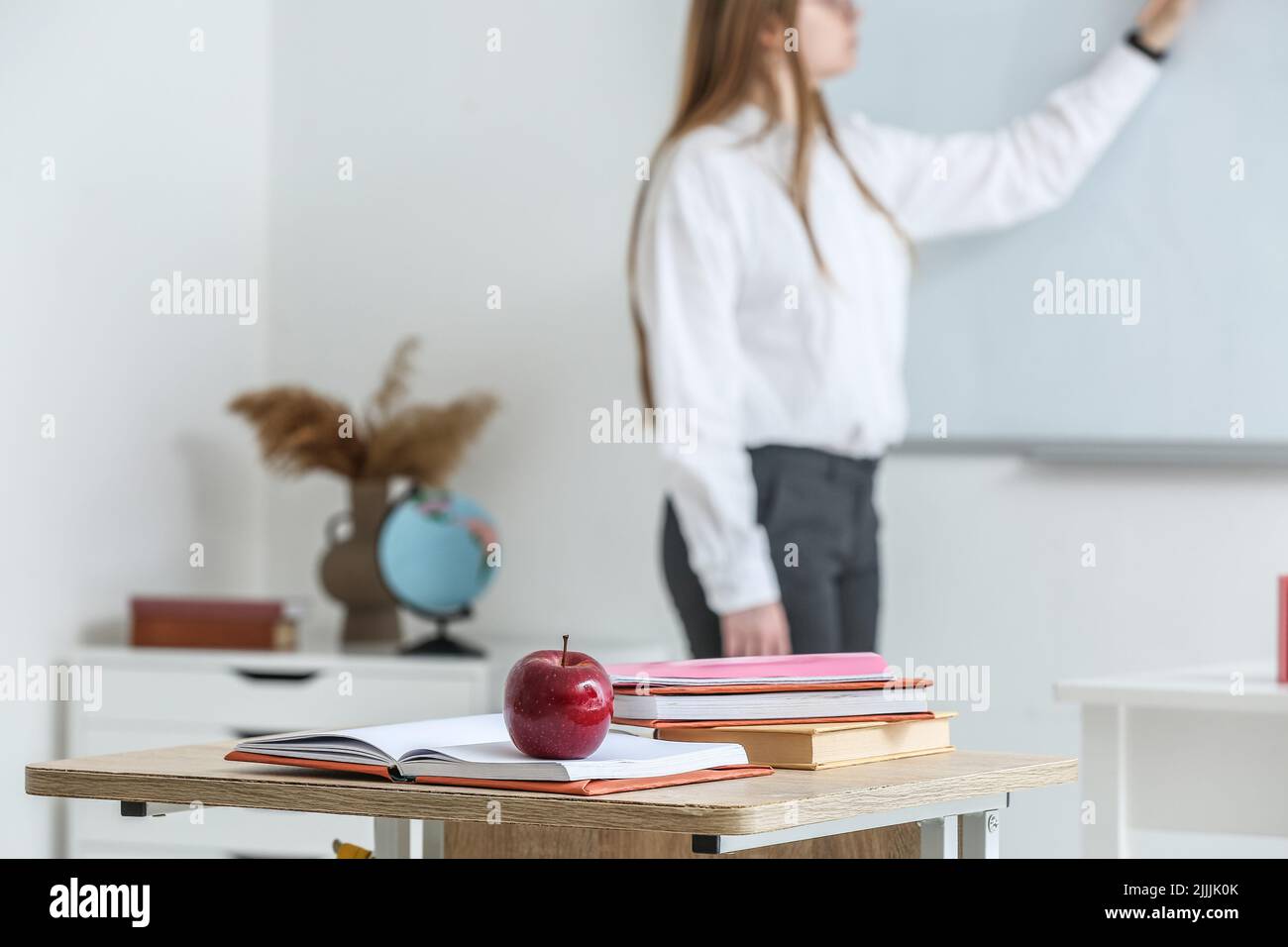 Apple with school books on table in classroom Stock Photo - Alamy