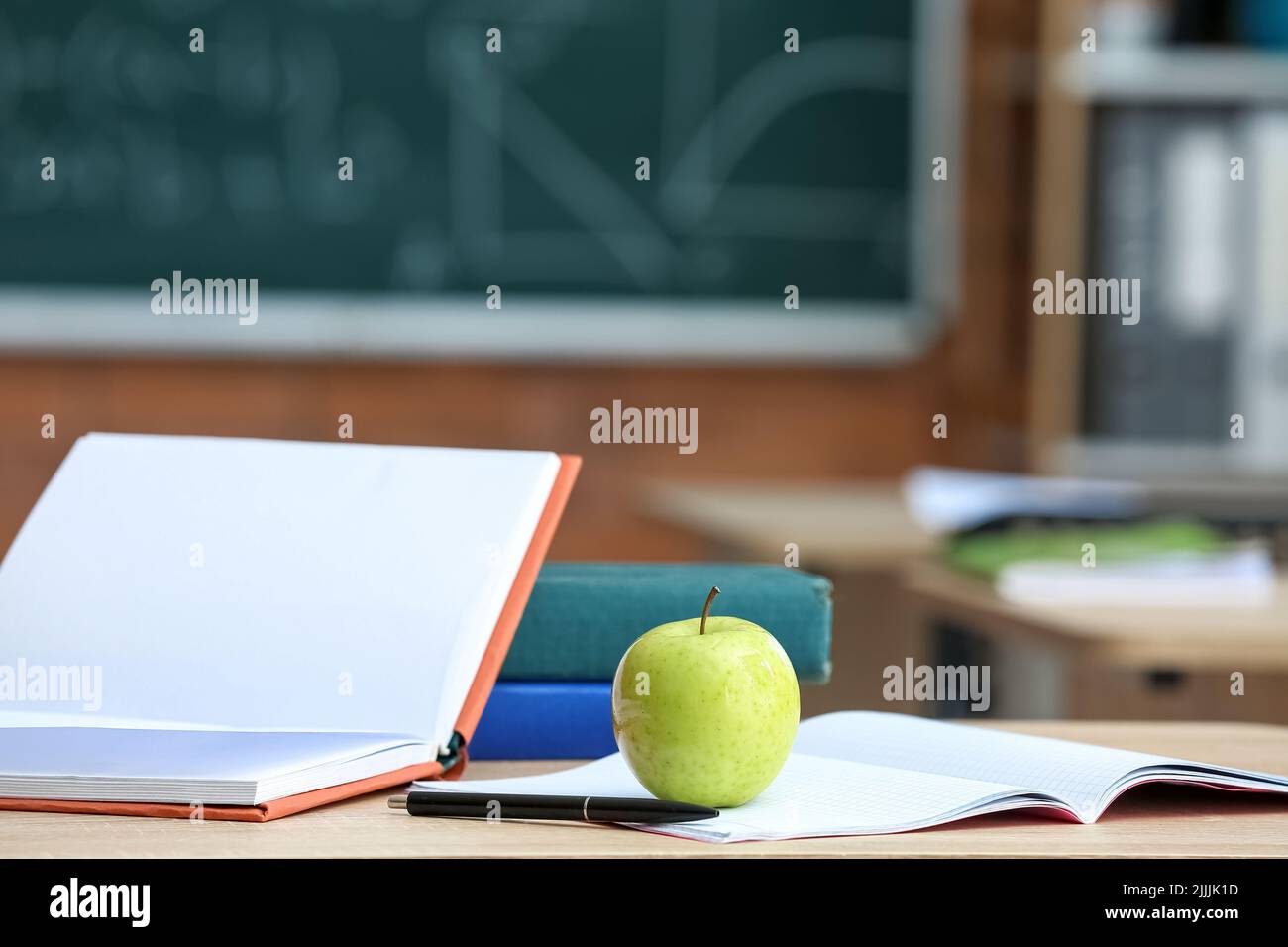 Apple with books on table in classroom Stock Photo - Alamy