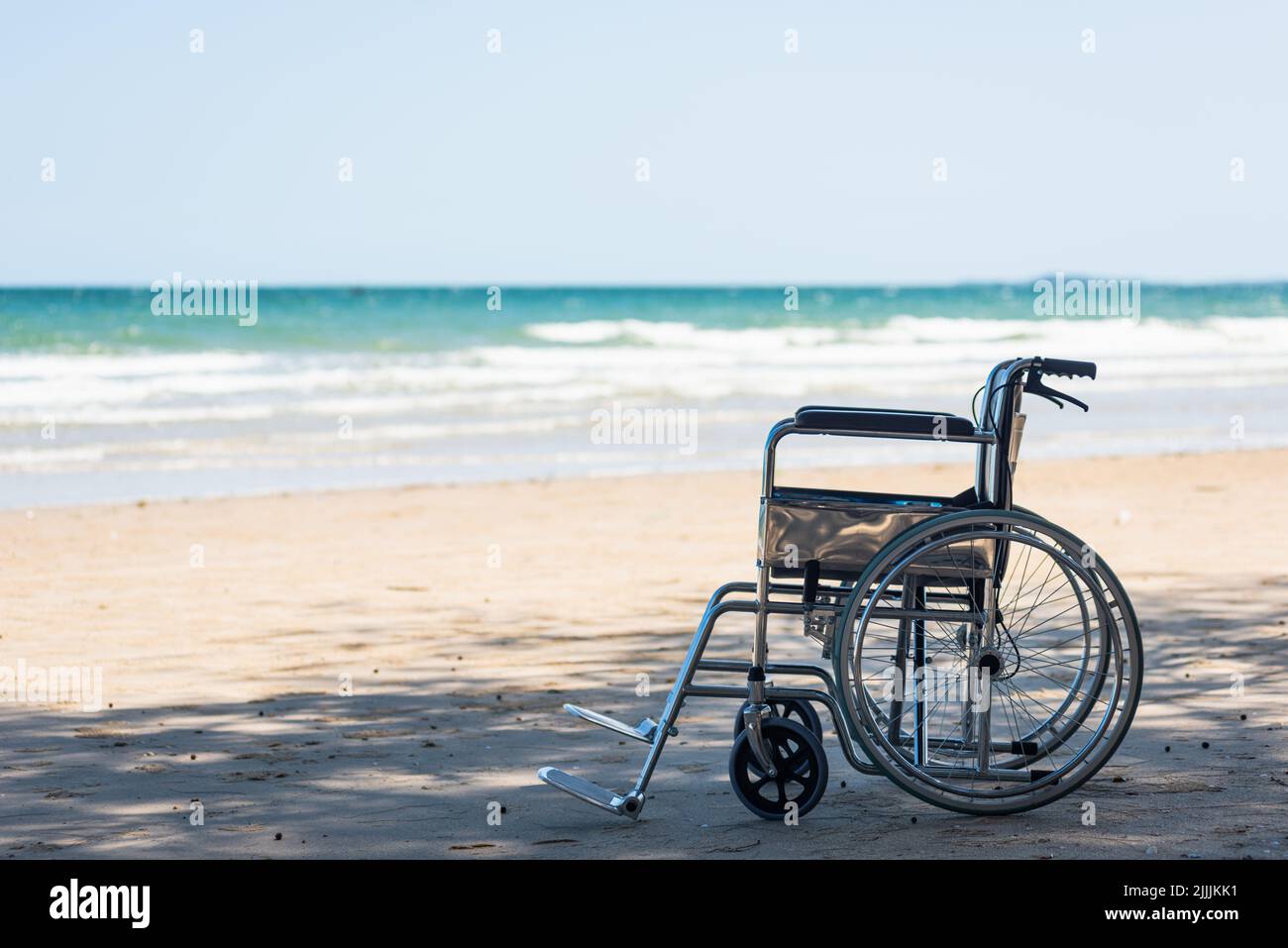Empty nobody wheelchair on sand of the beach for taking the patient ...