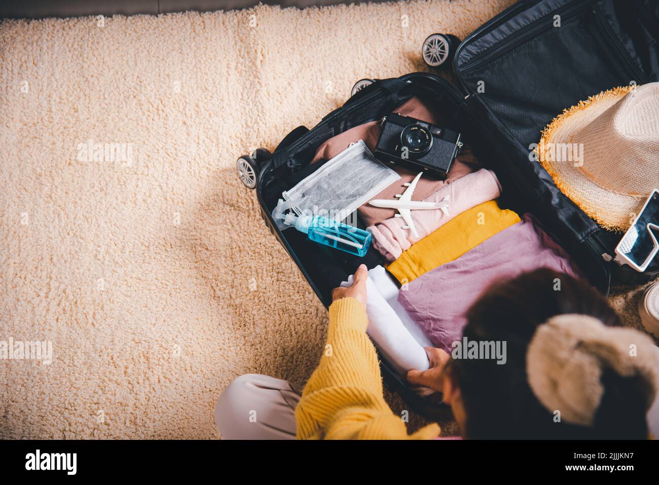Preparing for travel in new normal. Woman packing clothes in luggage ...