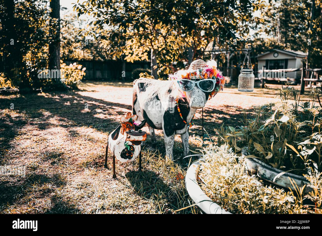 A view of cute decorations of cows in a garden with trees and plants ...