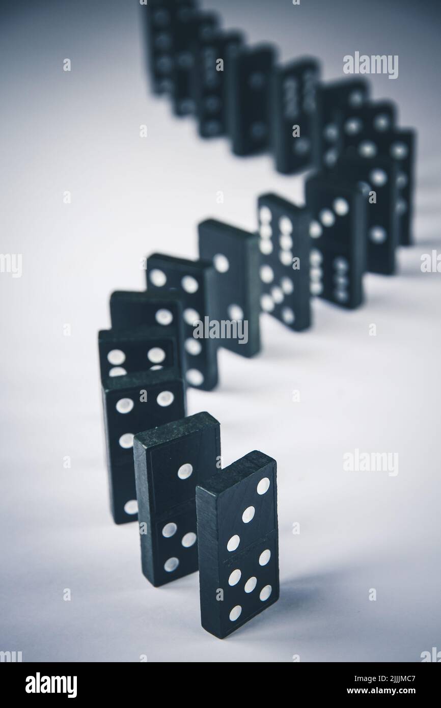 Black dominoes chain on a white table background. Domino effect concept ...