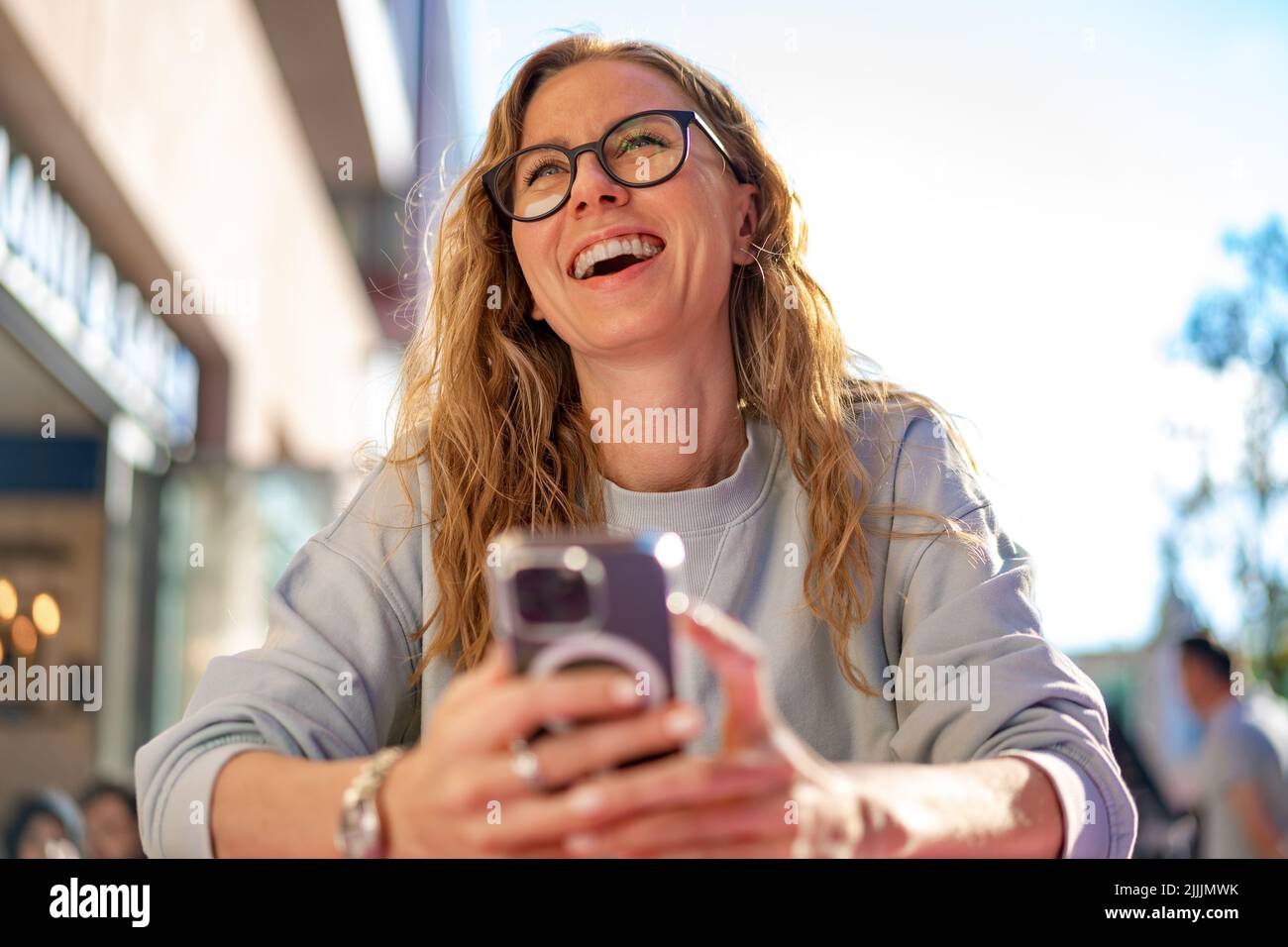 Young woman in a cafe reading a text message from her mobile phone ...