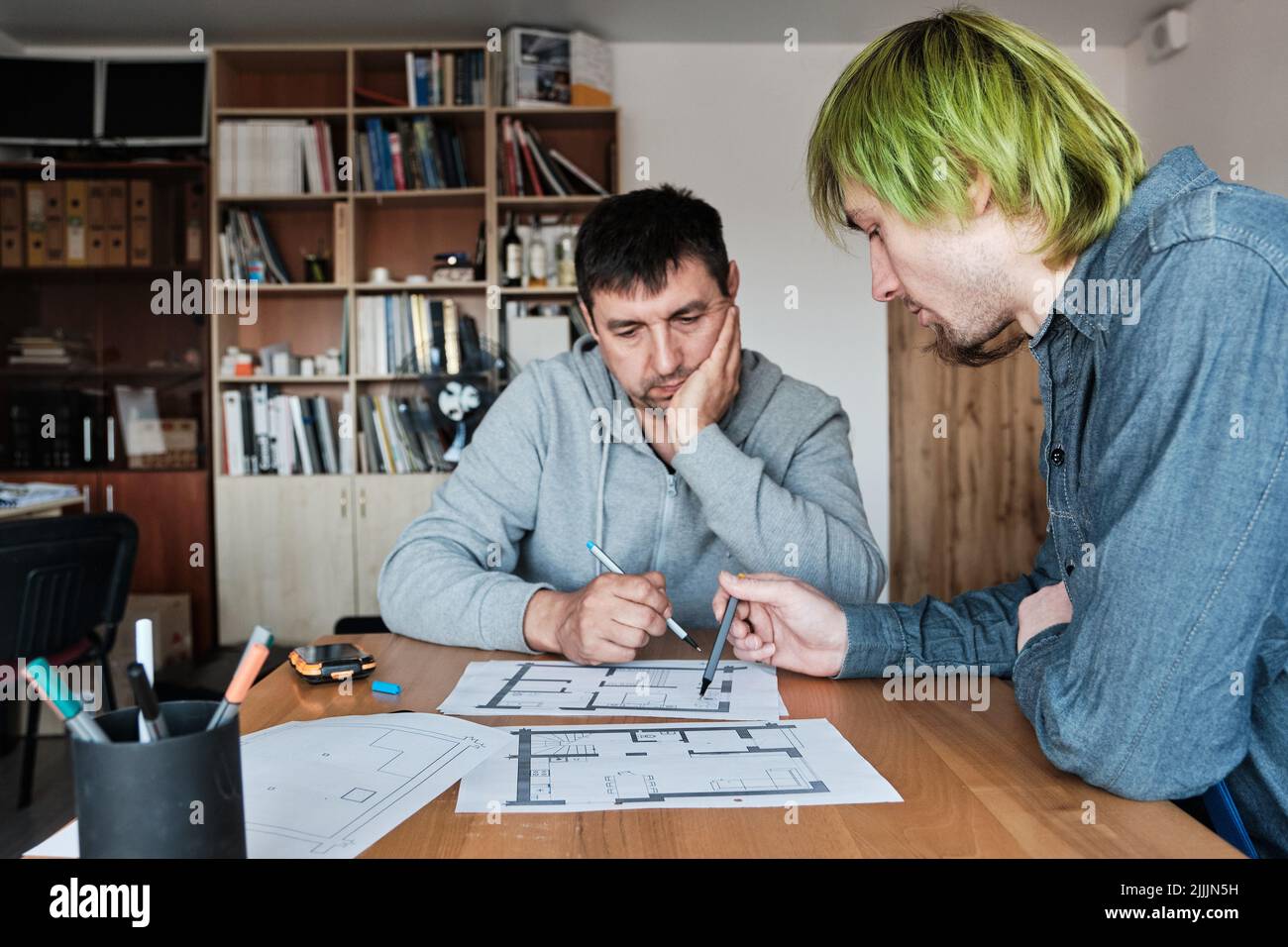 Two architects make marks on the plans of the building Stock Photo - Alamy