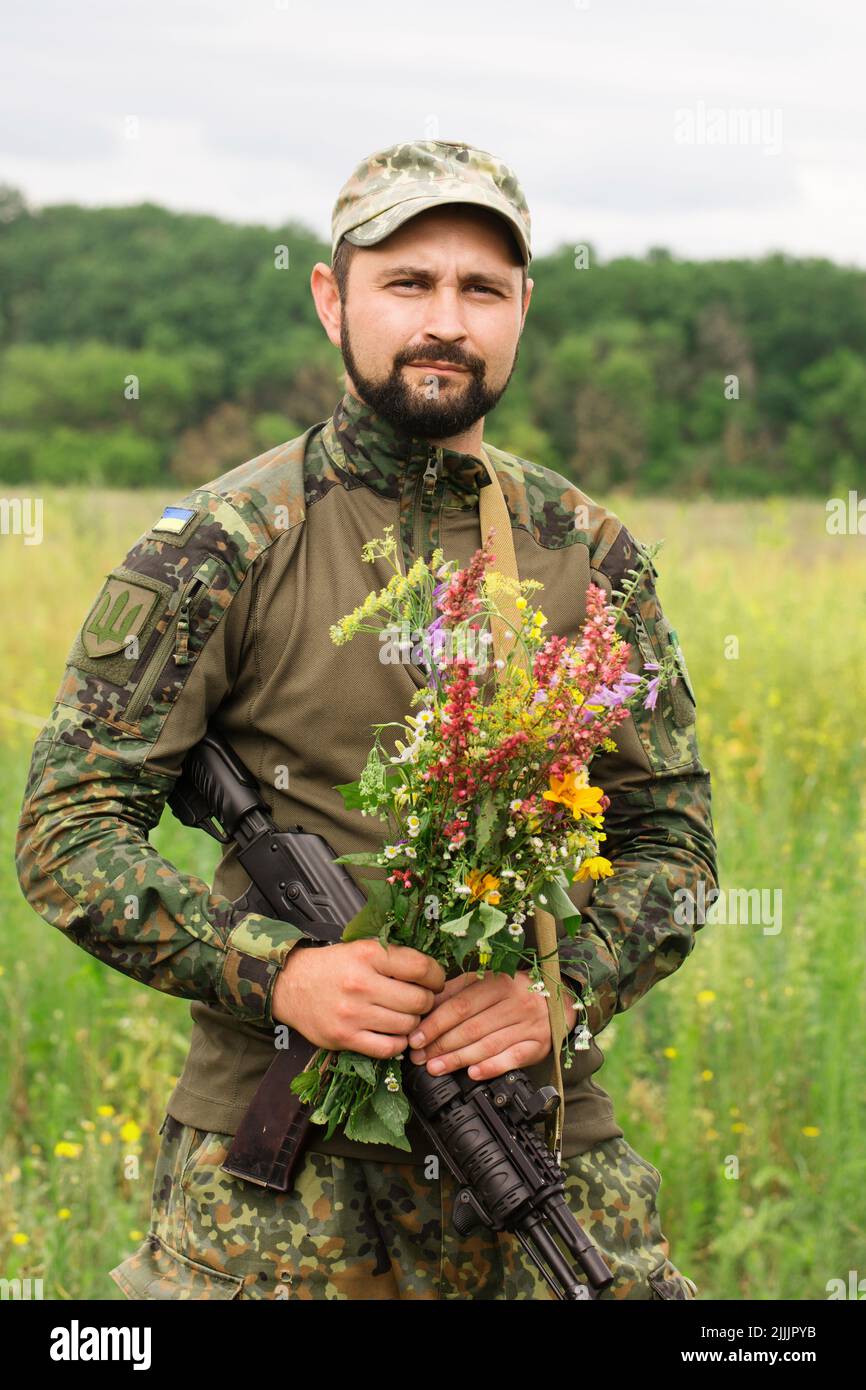 A Ukrainian soldier with a bouquet of wild flowers as a symbol of ...