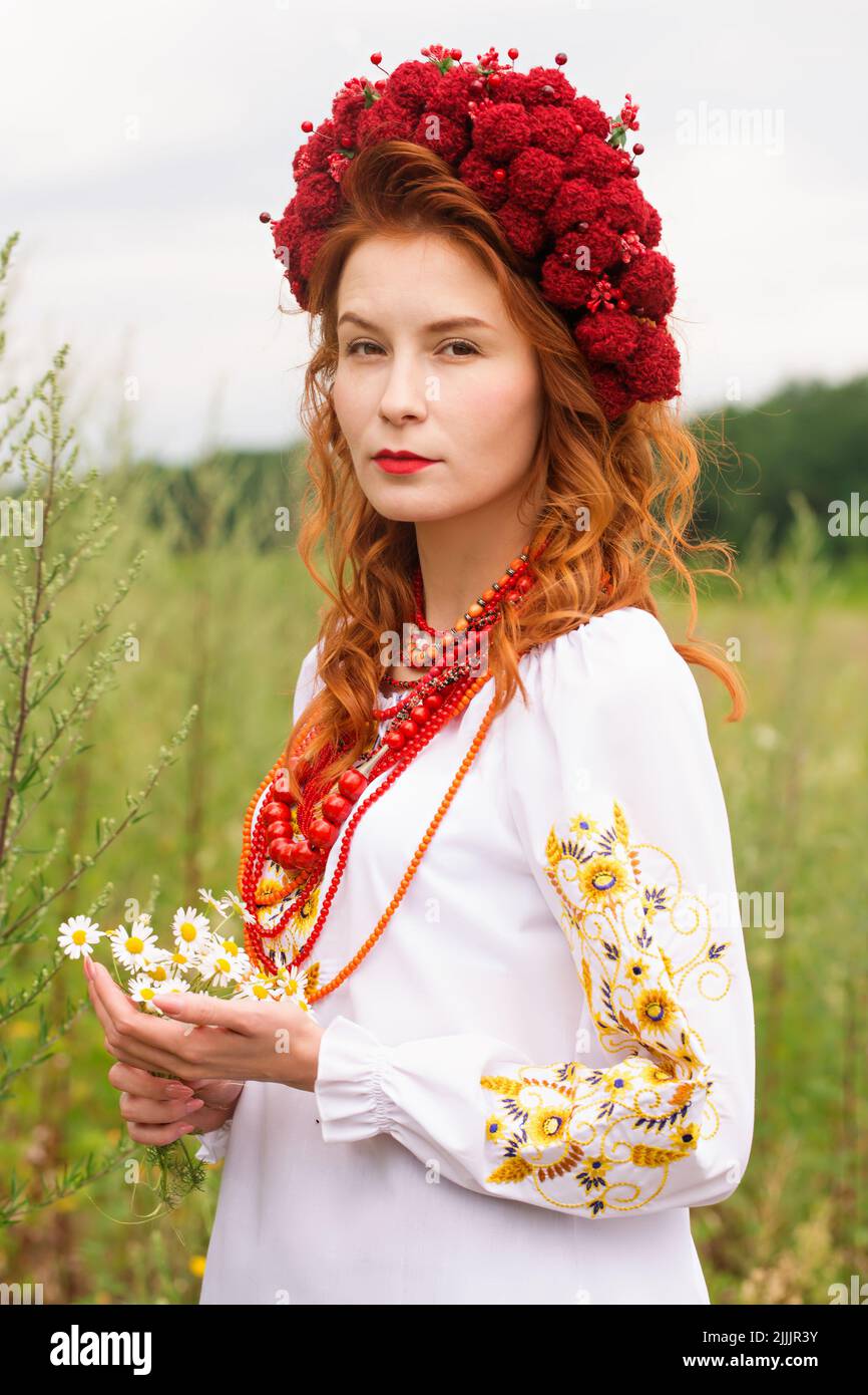 A beautiful red-haired Ukrainian woman in a folk dress with a bouquet ...