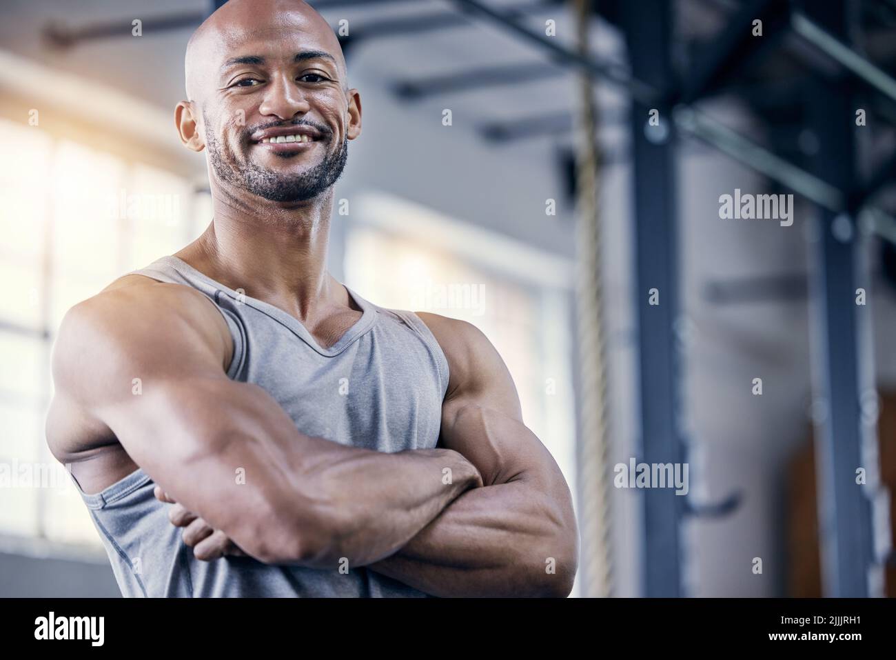 I can help you build a body like mine. Portrait of a muscular young man standing with his arms ...