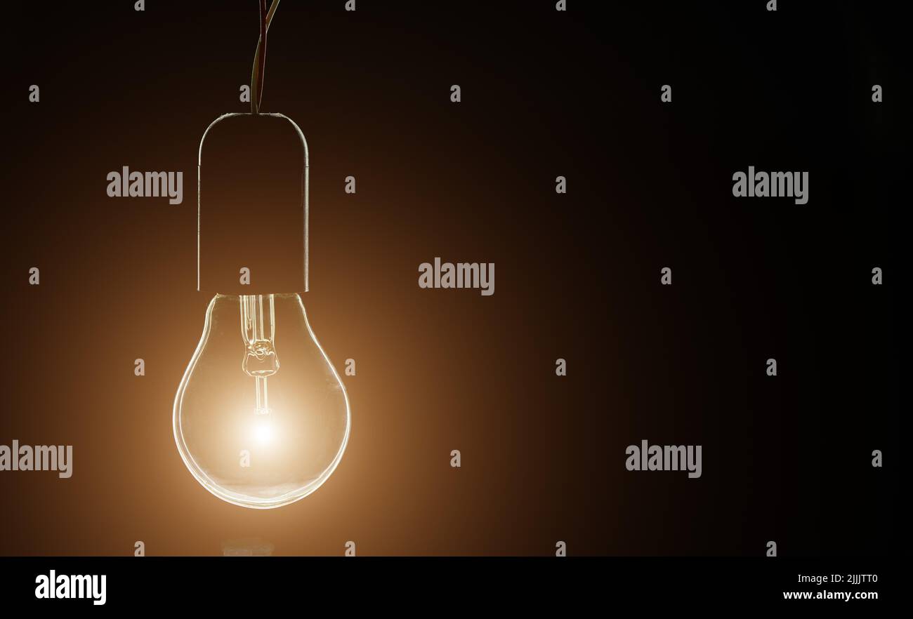 glowing incandescent light bulb on black background Stock Photo - Alamy