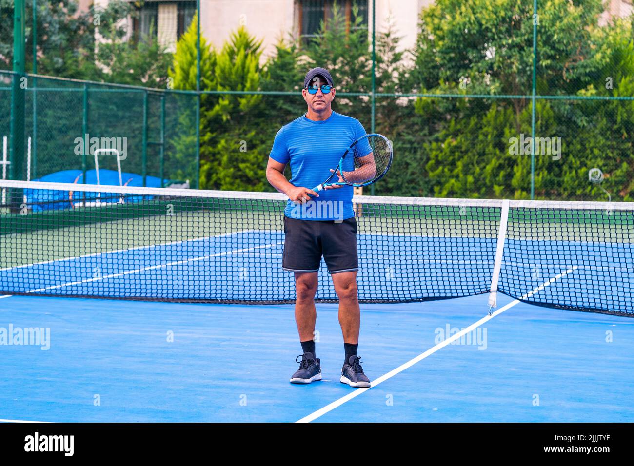 Portrait of middle aged positive male tennis player coach with racket ...