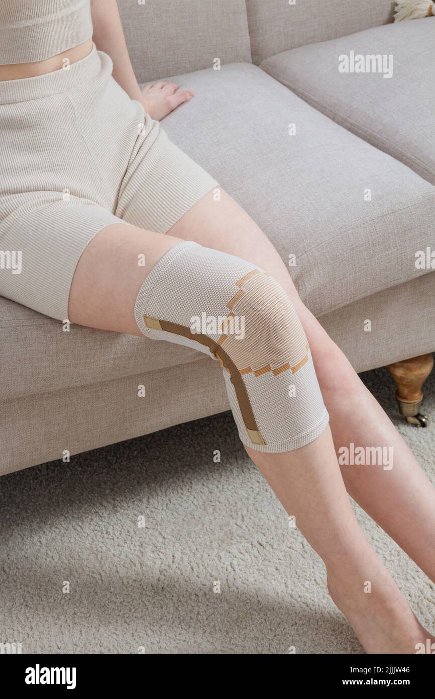 Knee support brace on a woman leg. girl in an orthosis in the interior ...