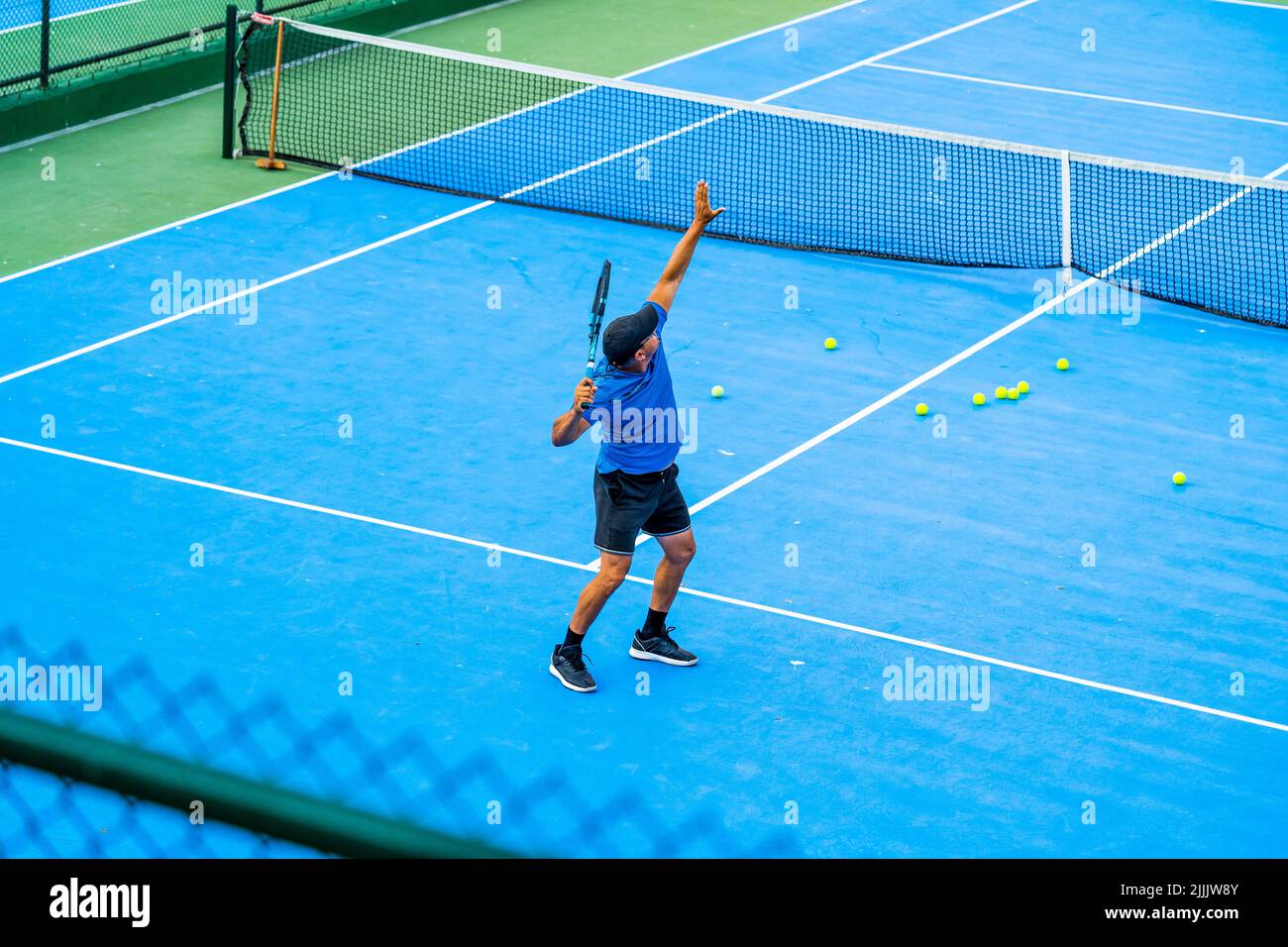 middle aged positive male tennis player coach with racket training at ...