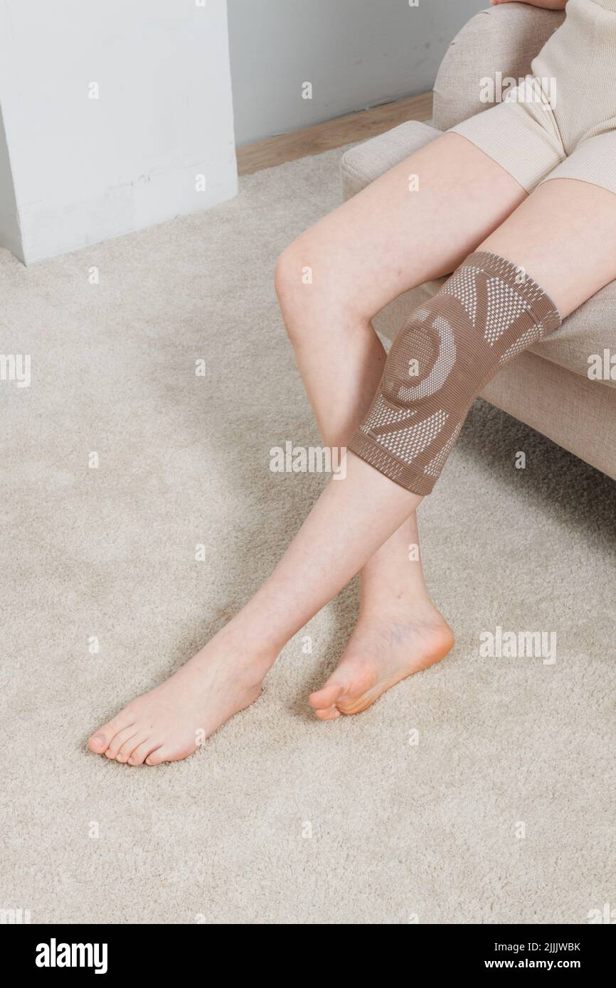 Knee support brace on a woman leg. girl in an orthosis in the interior ...
