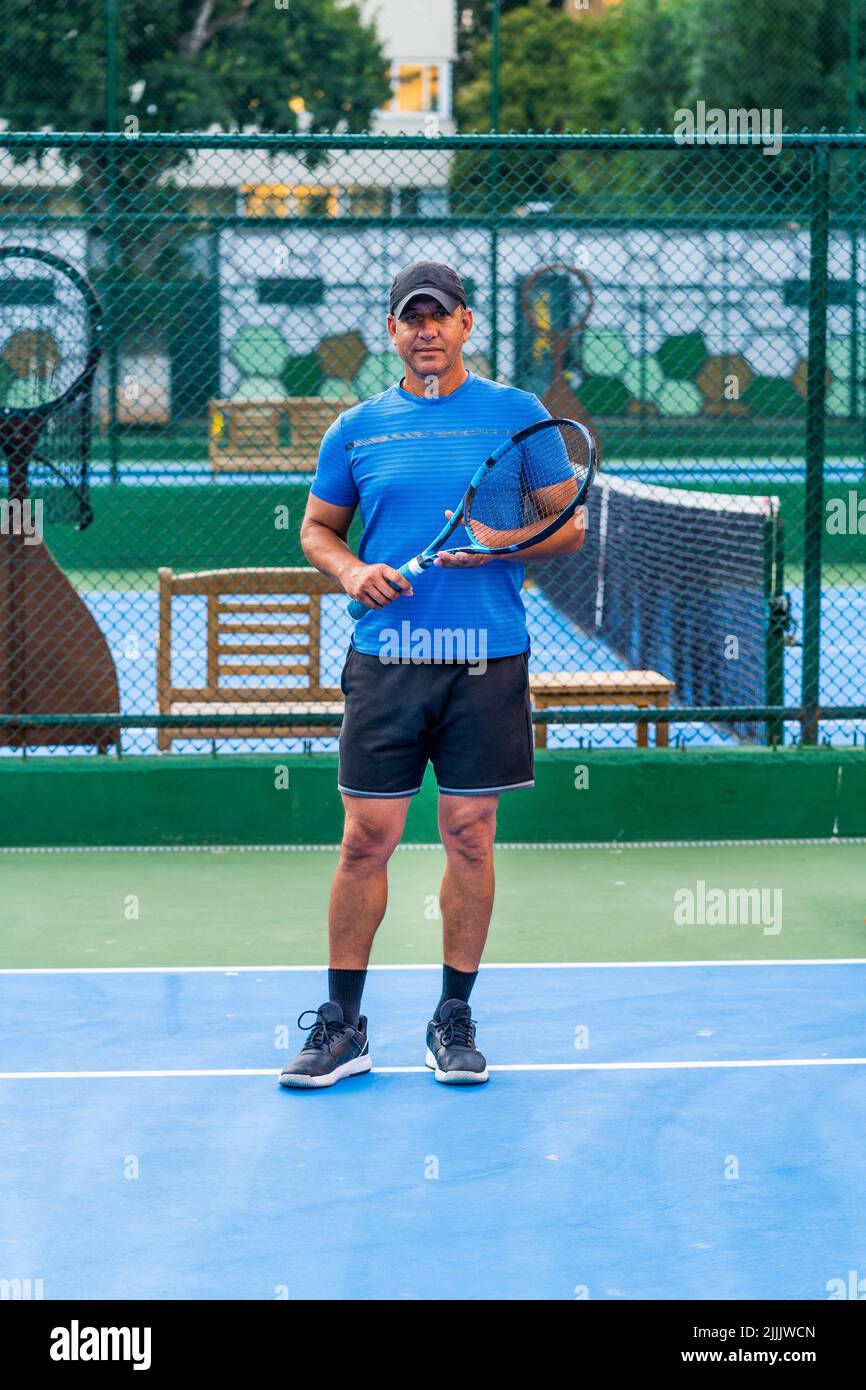 Portrait of middle aged positive male tennis player coach with racket ...